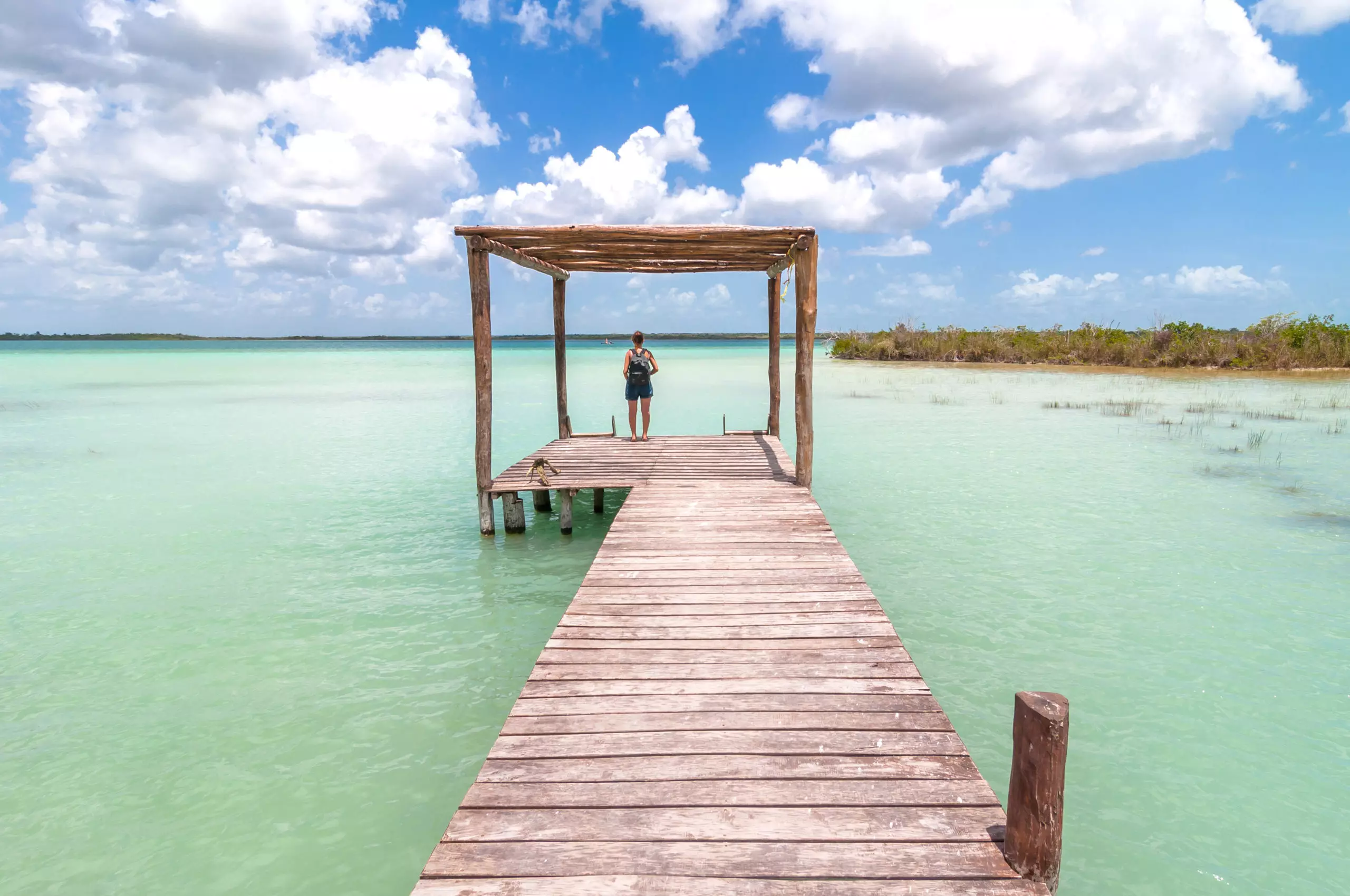 cais e mulher na lagoa Bacalar, México