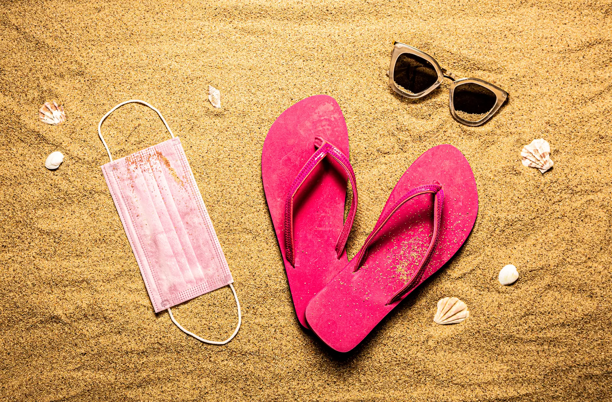 Chirurgisch gezichtsmasker, roze slippers en zonnebril – covid-19 vakantie